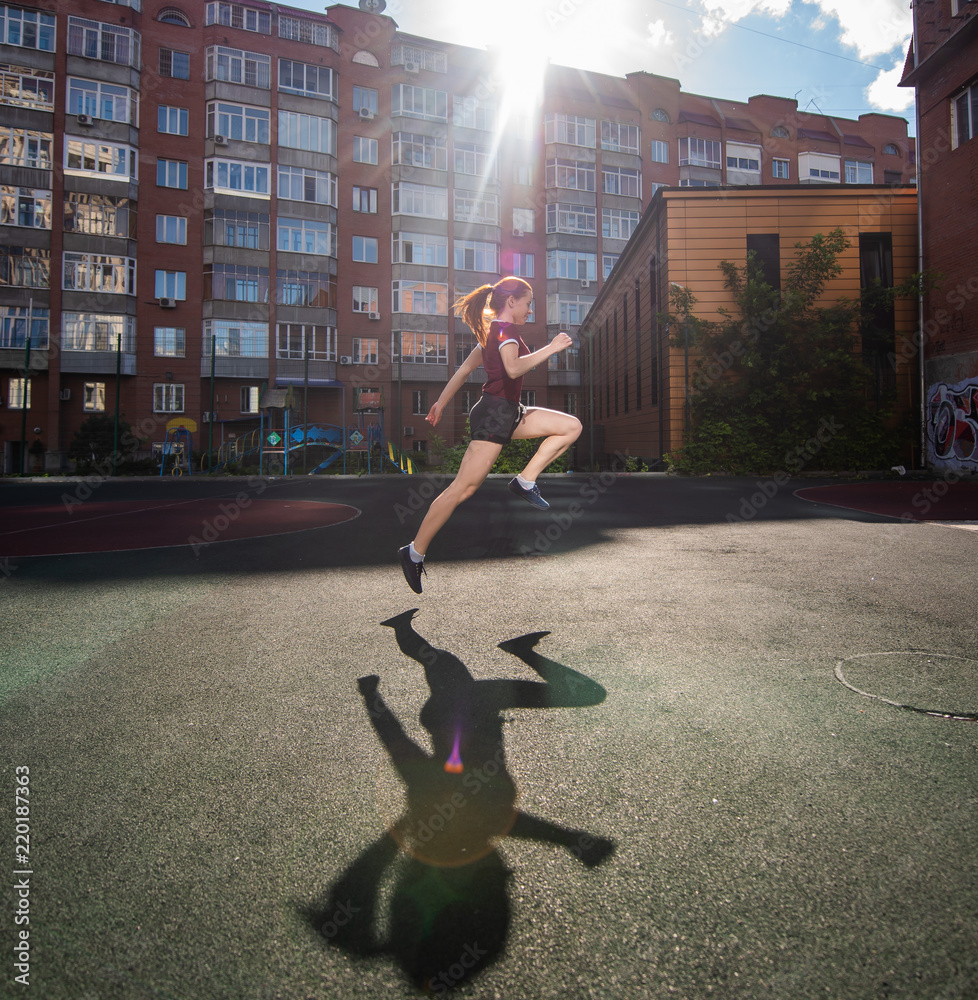 Red-haired young girl runs in the stadium. Student delivers standards ...