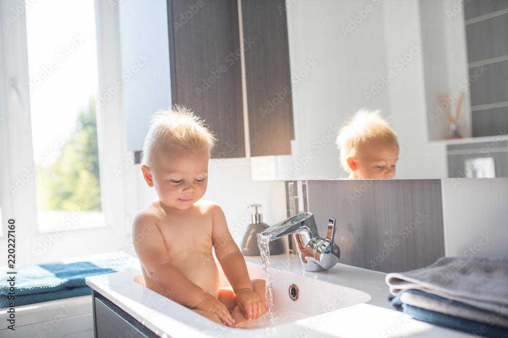 Baby taking bath in sink. Child playing with foam and soap bubbles in ...