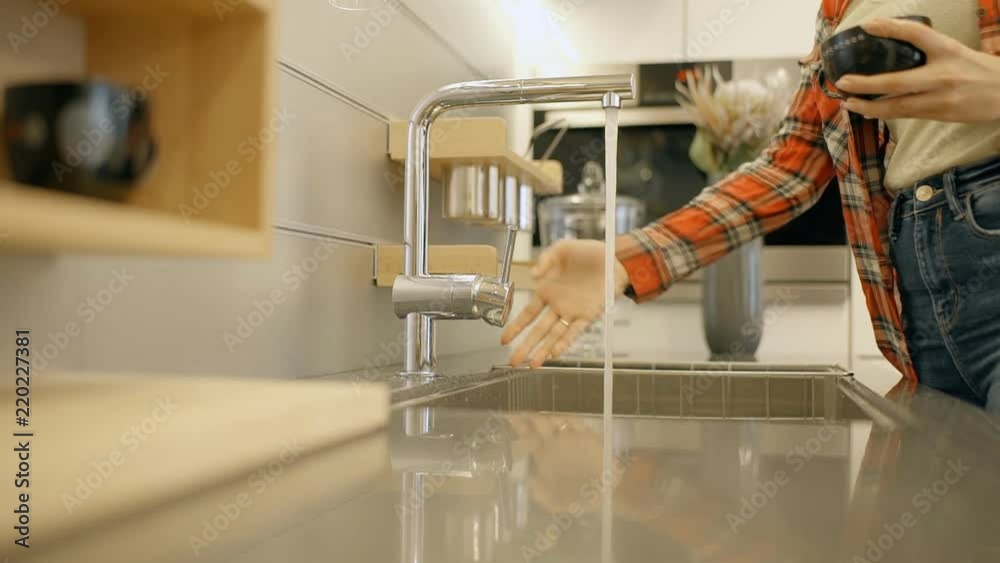 Housewife washing black mug in the kitchen at home. Woman in stylish ...