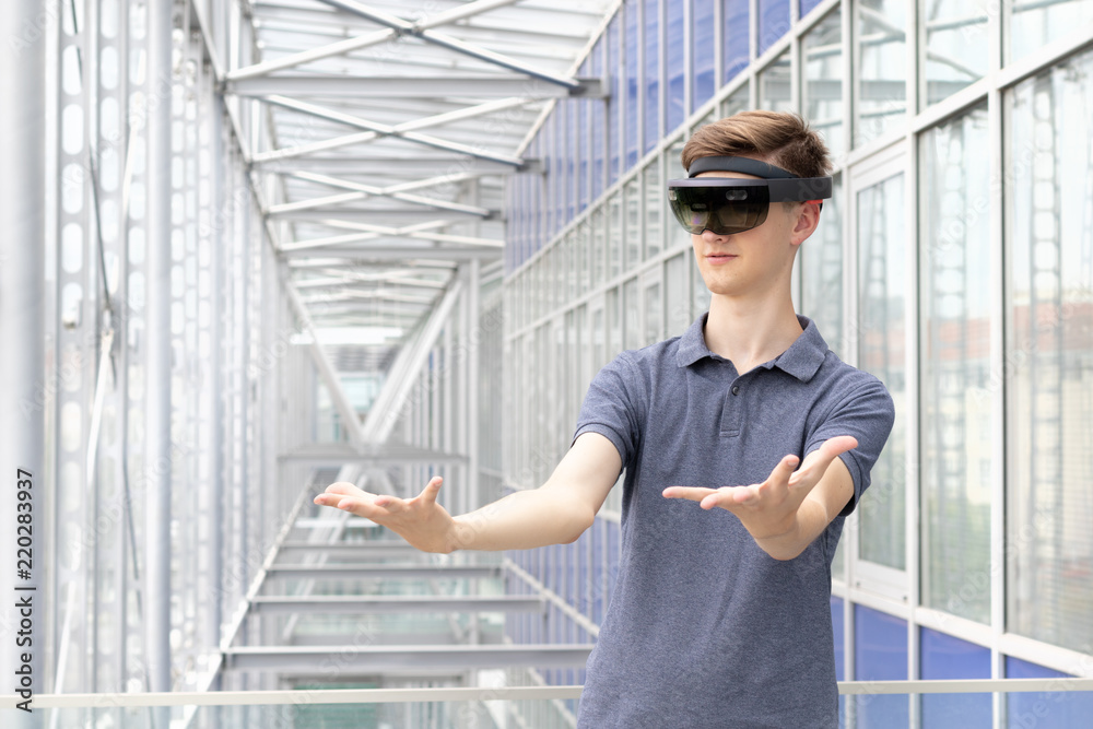 Teenager using augmented reality HoloLens in modern building. Goggles ...