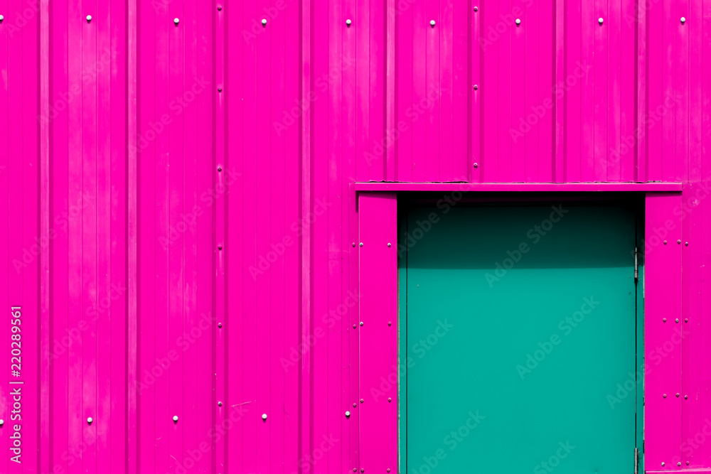 Modern industrialism. Neon pink building with green door. Vibrant paint ...