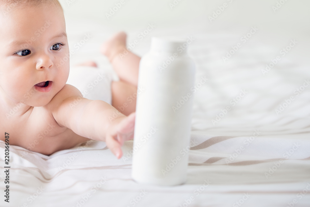 beautiful baby holding a bottle in the hand with care lotion tummy time ...