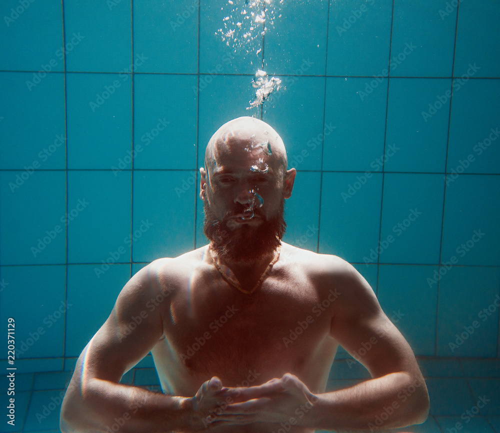 portrait of muscles beard yoga man underwater in the swimming pool ...