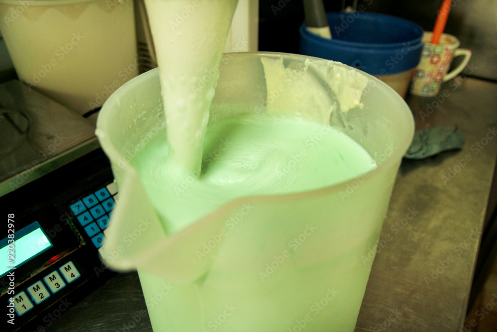 Female chef and worker is working at ice cream factory, she is mixing ...