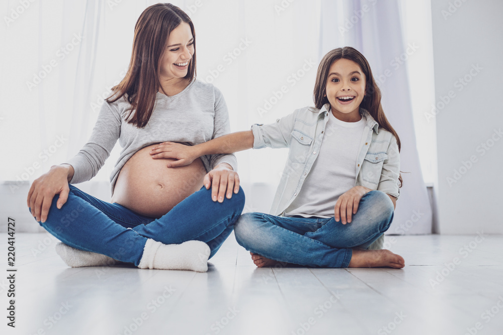 Sister inside. Full length of surprised positive girl sitting on floor ...