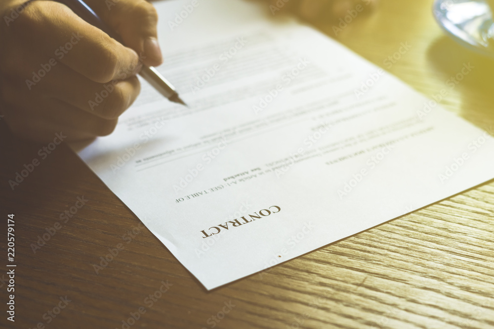 contract document, two men sign paper in the office a toned faded image ...