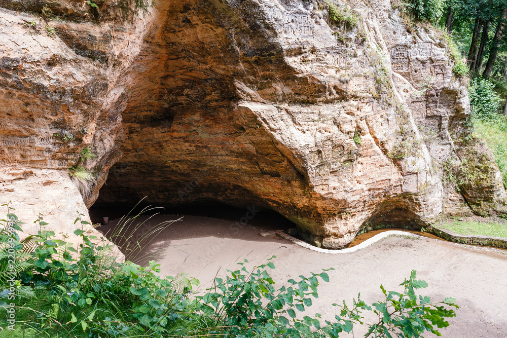 large, historic, open cave cliff wall with old, historical scratches ...