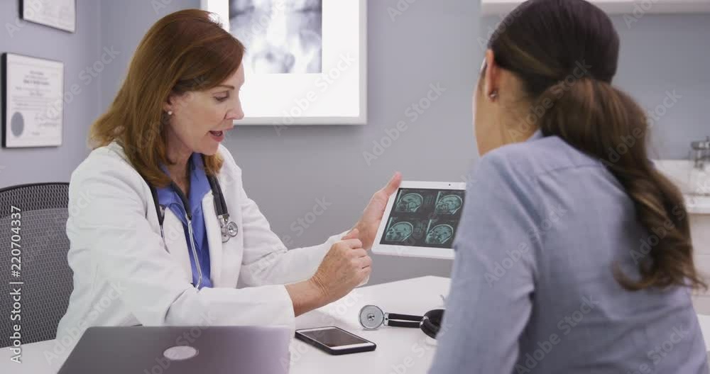 Young latina patient reviewing ct scan of cranium with middle aged ...