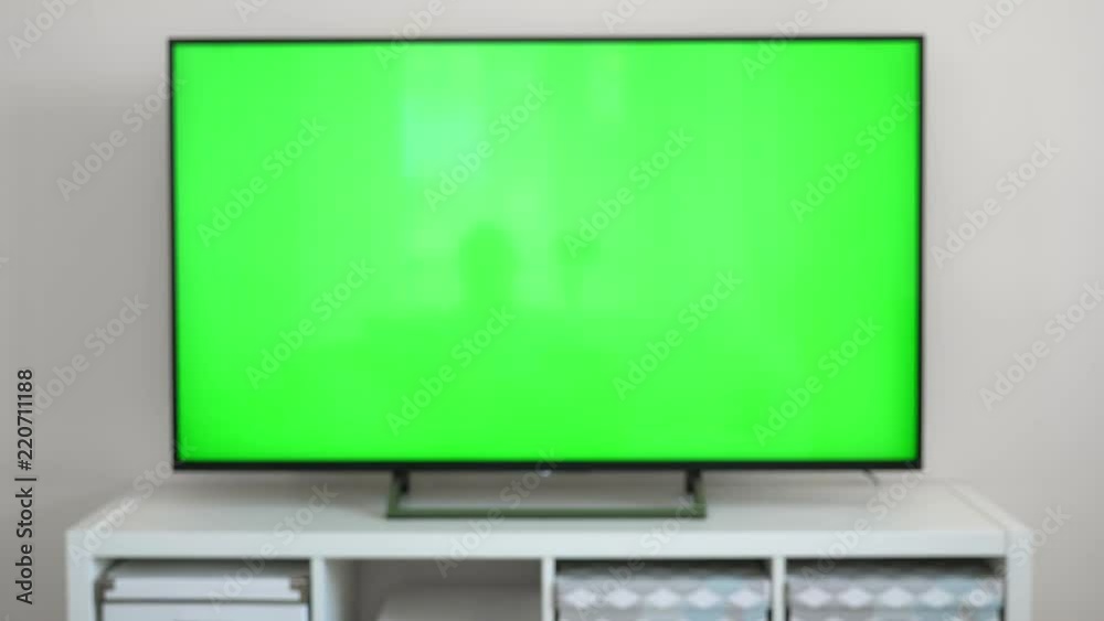 Watching tv with green screen at home interior. Push buttons on remote ...