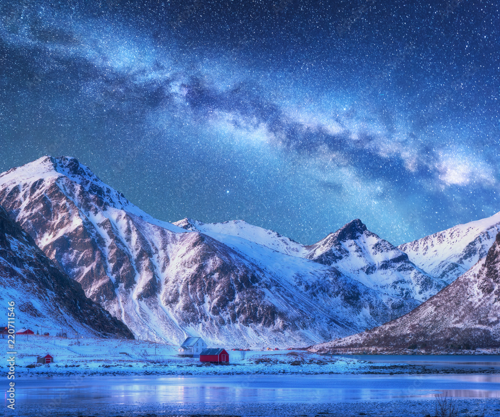 Milky Way above houses and snow covered mountains in winter at night ...