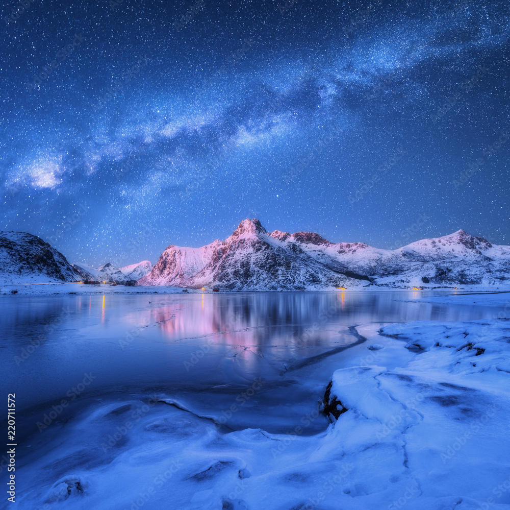 Milky Way above frozen sea coast and snow covered mountains in winter ...