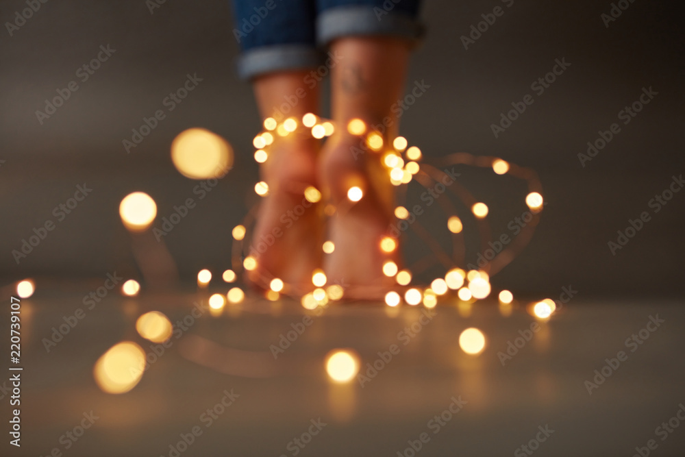 Christmas composition of female feet with garlands on the floor around ...