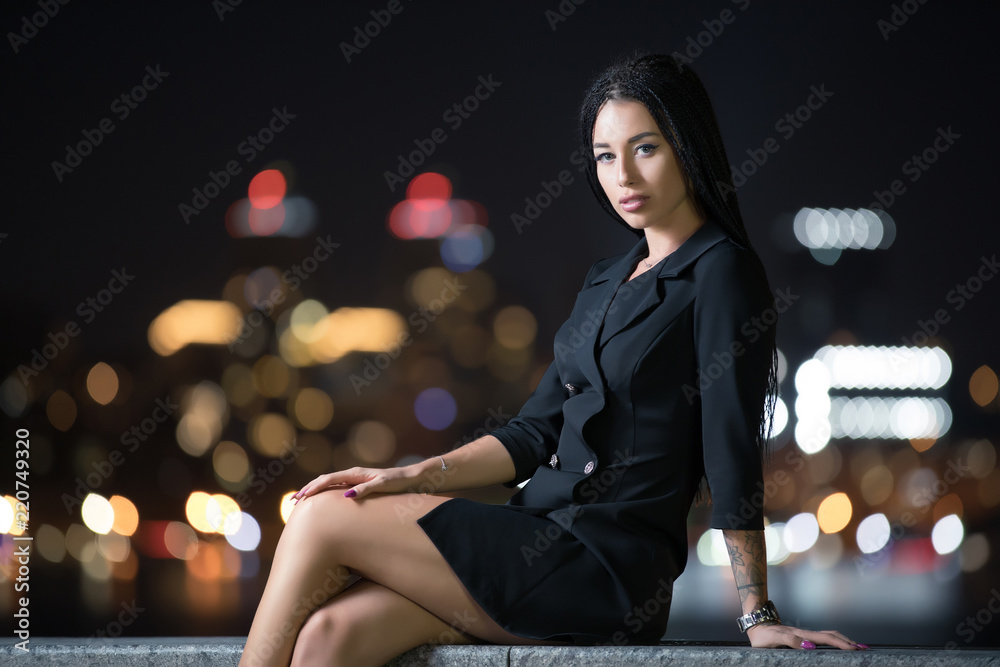 Sexy woman sitting in strict dress at night city Stock Photo | Adobe Stock