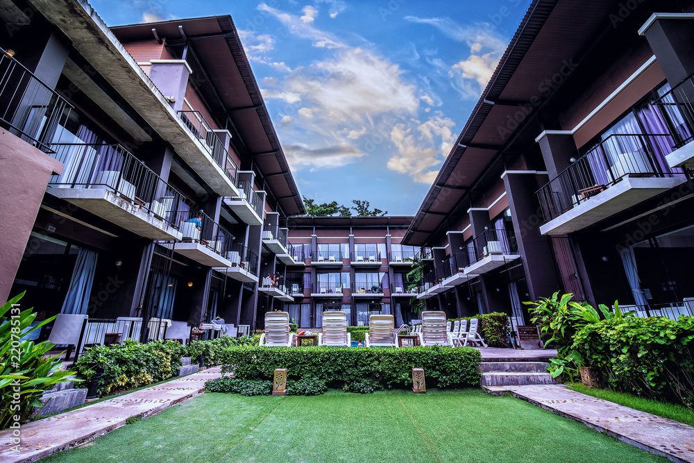 poolside resort building with swimming pool and pool chairs along pool ...
