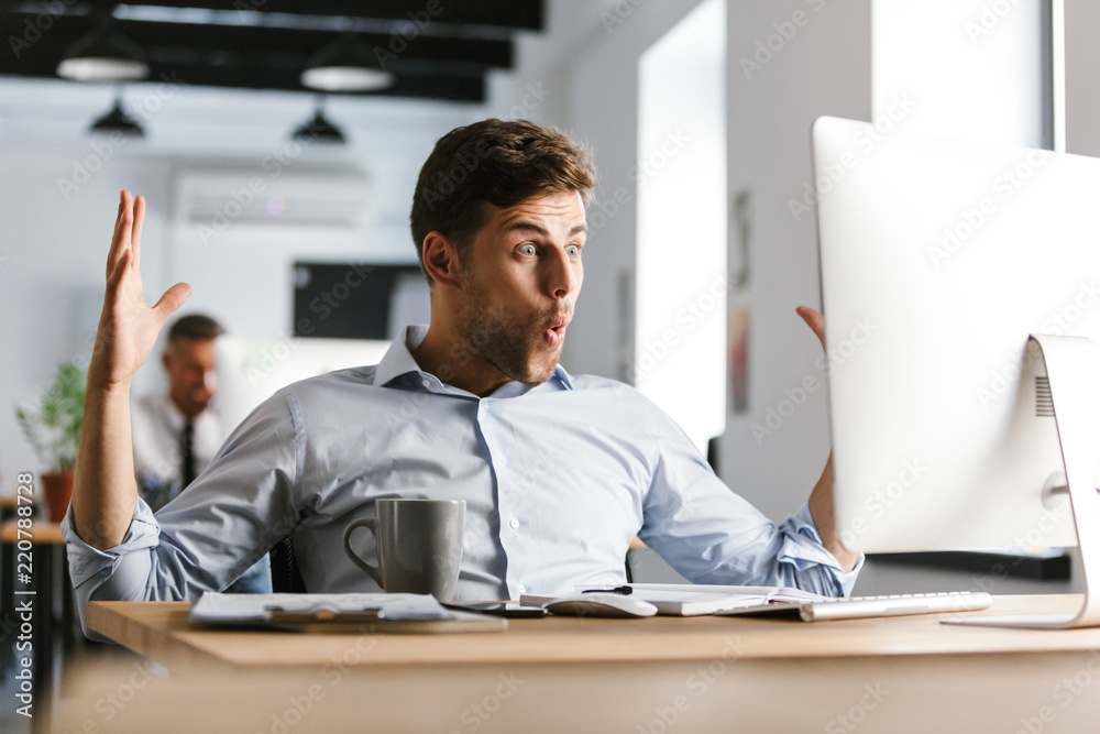 Image of Surprised happy male manager using computer Stock Photo ...