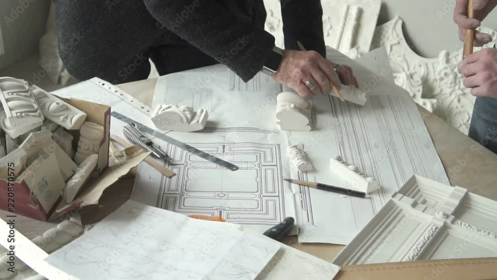 Hands of two male architects working with white plaster molding samples ...