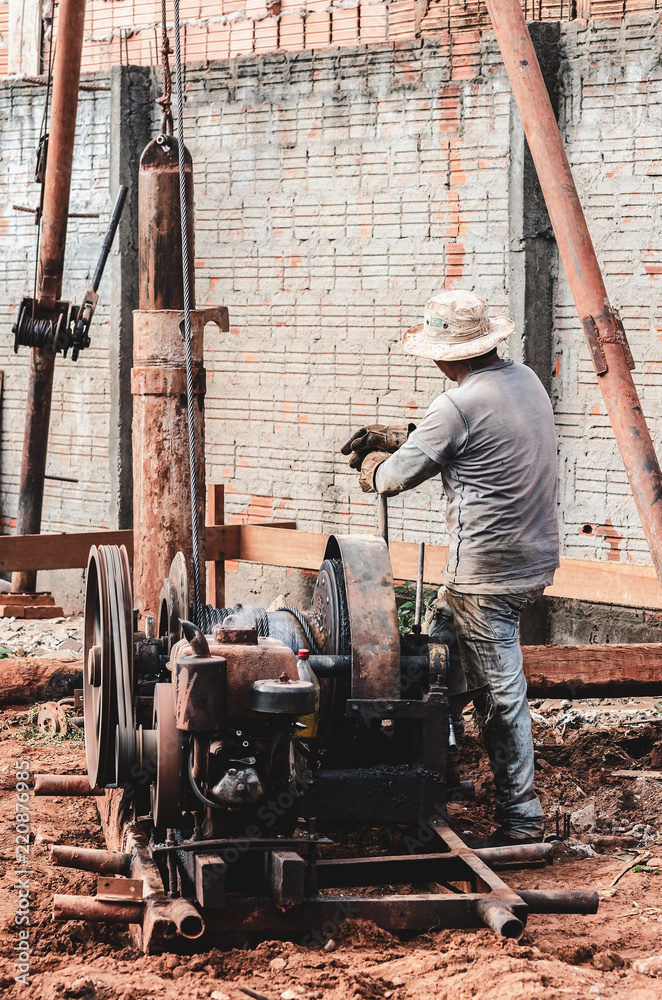 Construction worker using a pile driver (bate-estaca)to dig the soil ...