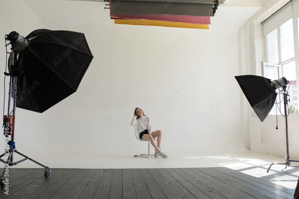Model is sitting and posing in a professional photo studio on a white ...