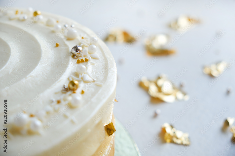 Cake with white cream, decorated with silver and gold confectionery ...
