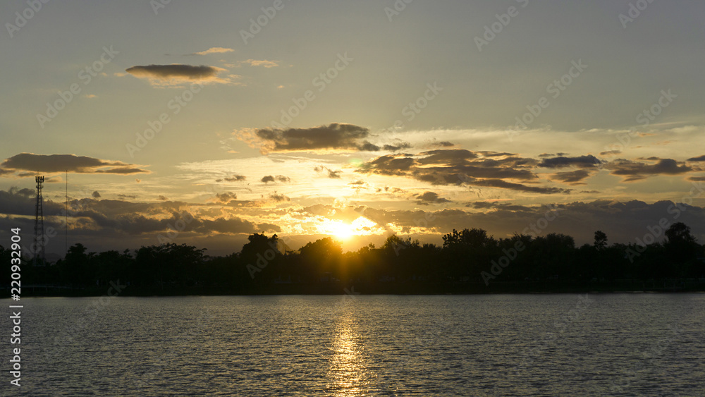 Sunset scene over lake water surface and Fire pole and tree shadowÂ ...