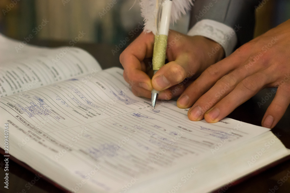 The groom signs the marriage registration documents. Young couple ...