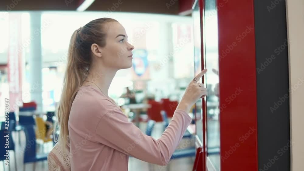 Young blonde girl ordering food in fast food restaurant using self ...