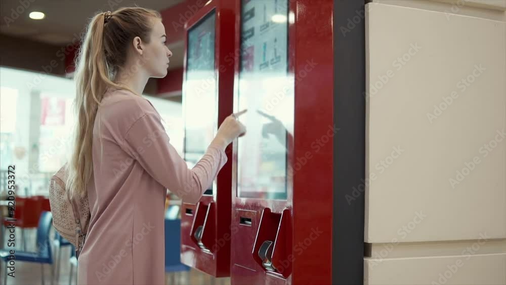 Female customer is using automat for ordering in fast-food cafe ...