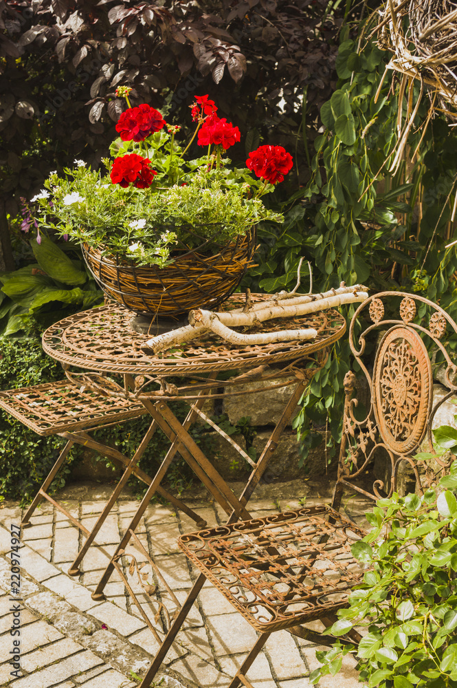idyllische Sitzecke im Garten mit Blumengesteck und Tisch Stühle im ...