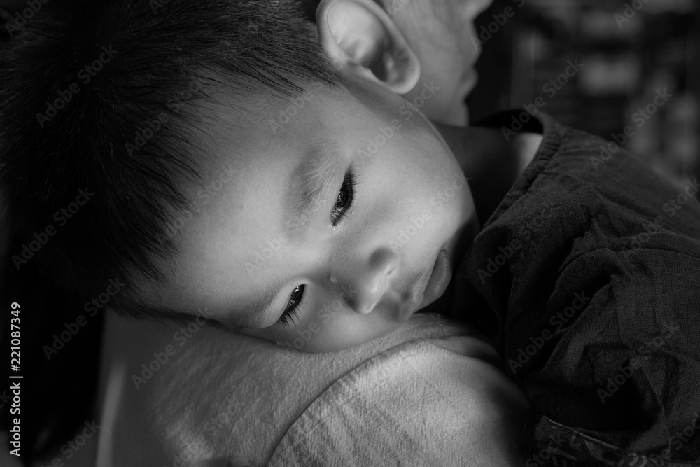 Asian mom cuddle her crying son, his head snuggle on her shoulder. love ...