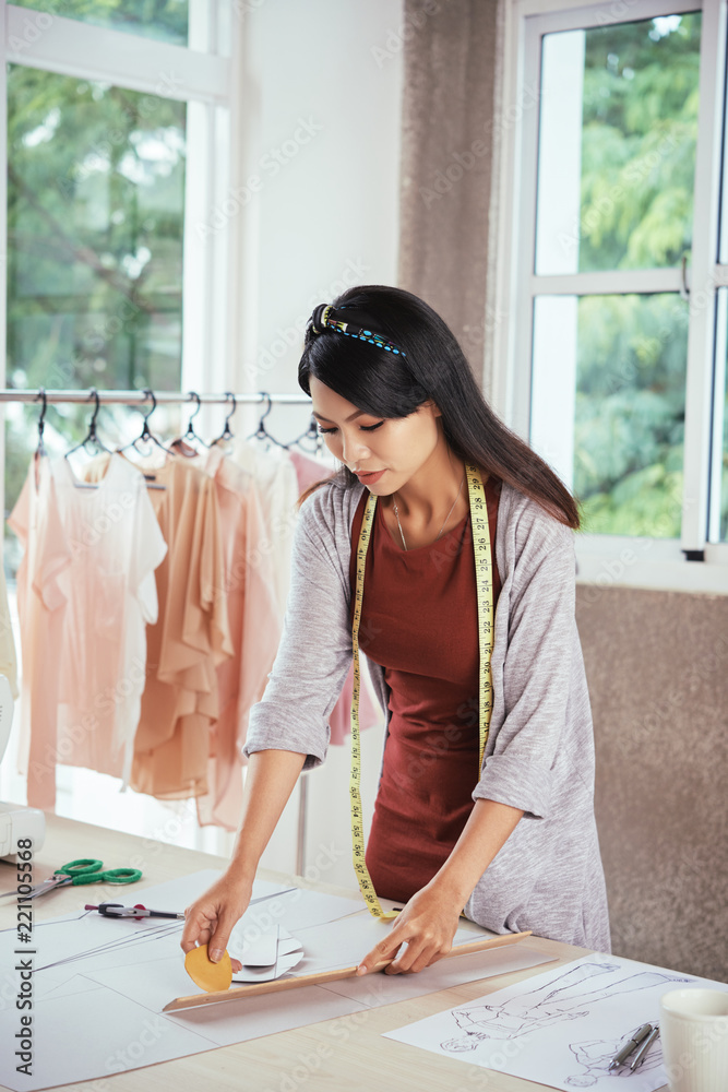 Young Asian woman using chalk and ruler to draw patterns for custom ...