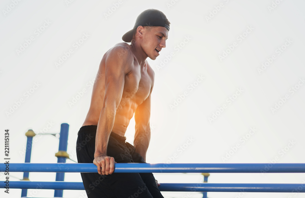 Side view of young fitness muscular man doing exercises on horizontal ...