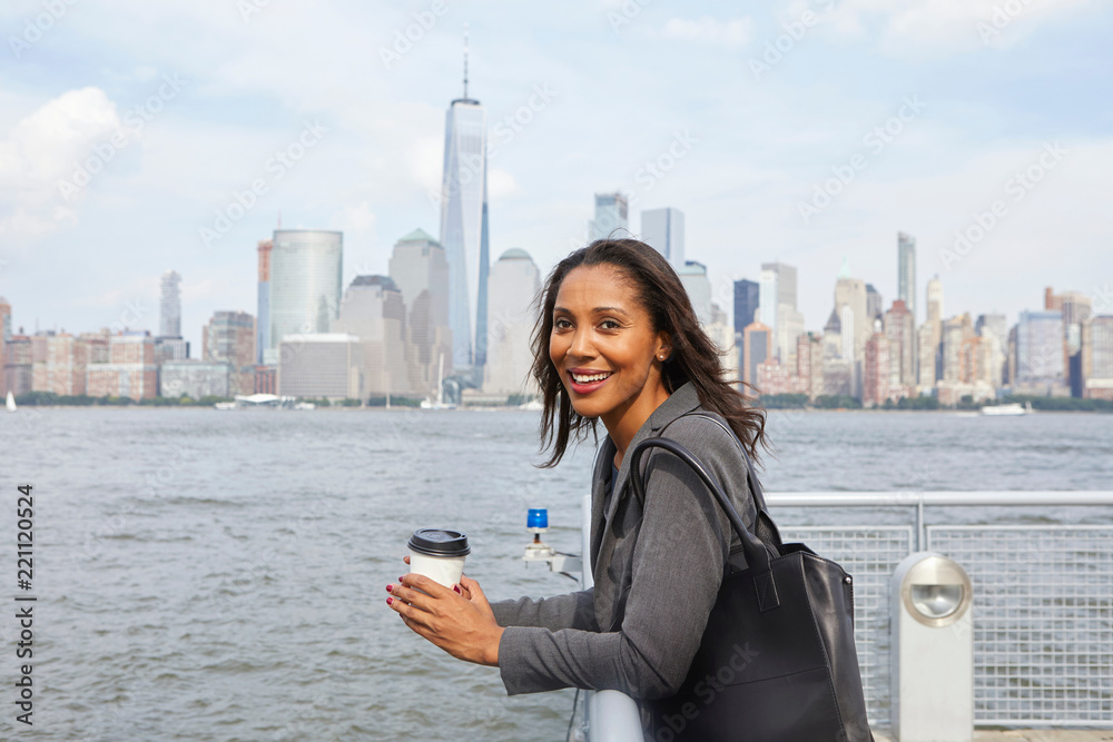 Businesswoman taking coffee break, New York City skyline in background ...