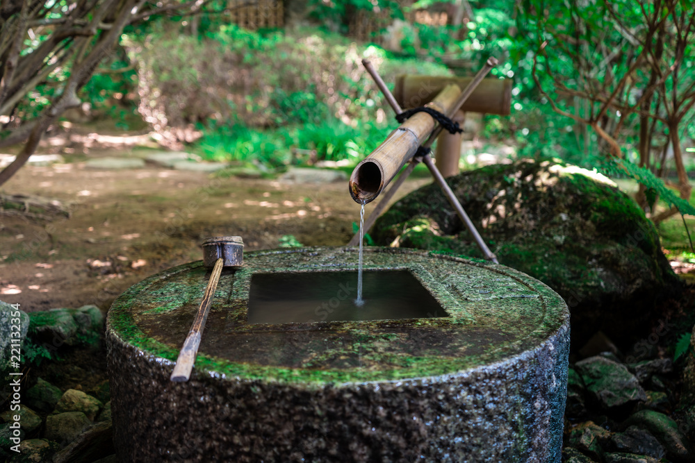Ancient Zen stone wash basin with Japanese writings and water coming ...