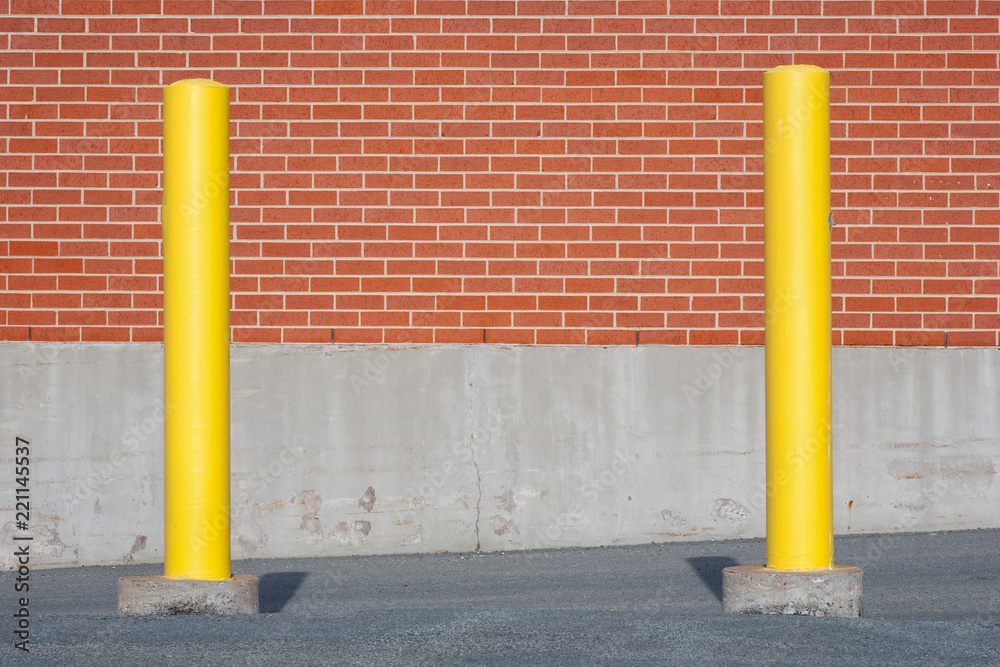 Yellow traffic bollards in front of brick building wall. Stock Photo ...