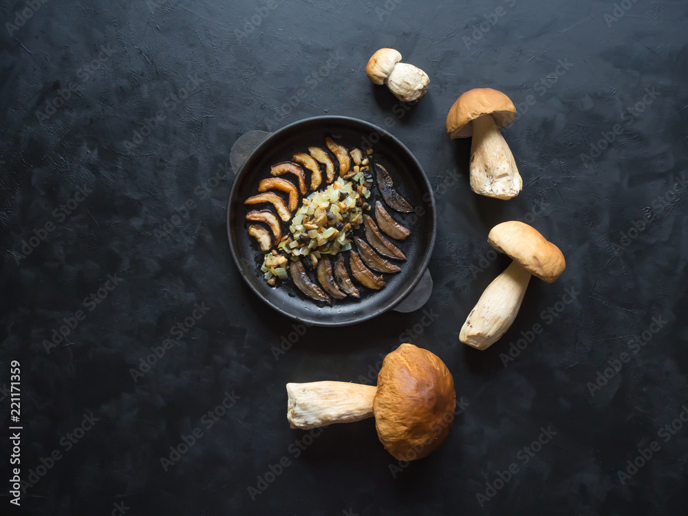 Cooking penny bun. Fried cepes in a iron pan on the black table. Top ...