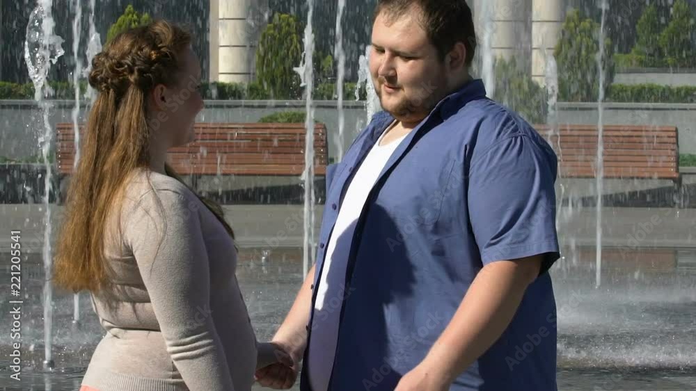 Romantic couple of overweight people kissing and hugging outdoors ...