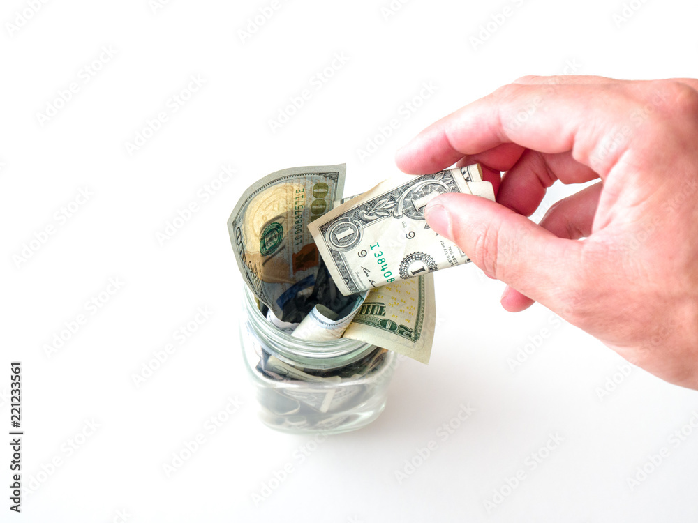 A white Caucasian male hand putting a dollar bill into a glass mason ...