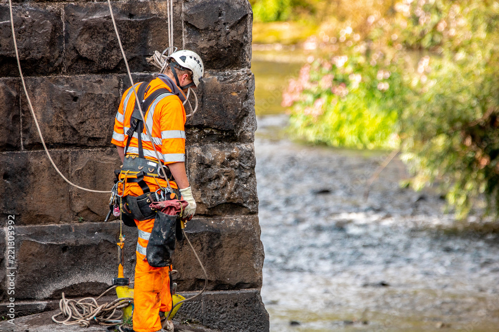 Rail bridge worker attached to safety harness wearing full PPE Stock ...