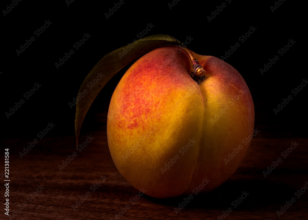 Peach still life one fruit seen from the side against black background ...