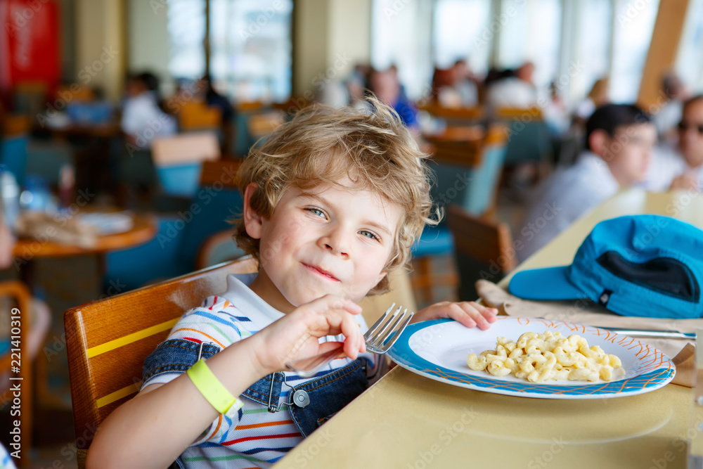 Cute healthy preschool kid boy eats pasta noodles sitting in school or ...