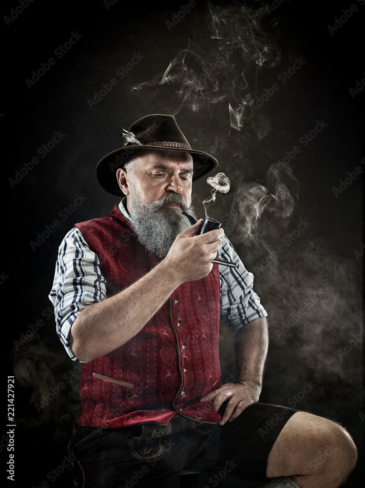 dramatic portrait of gray bearded senior man in hat smoking tobacco ...