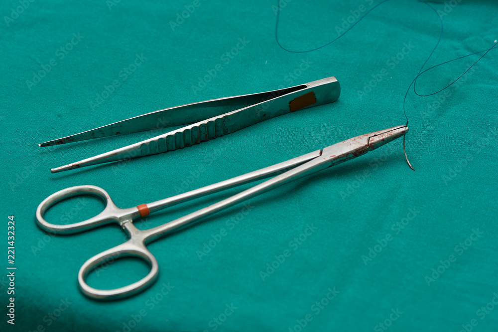 Needle holder and forceps on surgical table Stock Photo | Adobe Stock