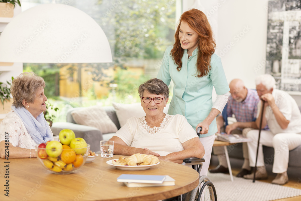 Professional medical caretaker in uniform helping smiling senior woman ...