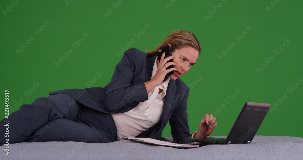 White woman in business suit making phone call on her bed on green ...