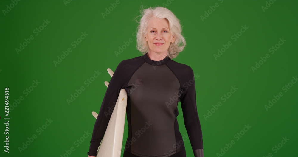 Confident old female surfer posing with surfboard on green screen Stock ...