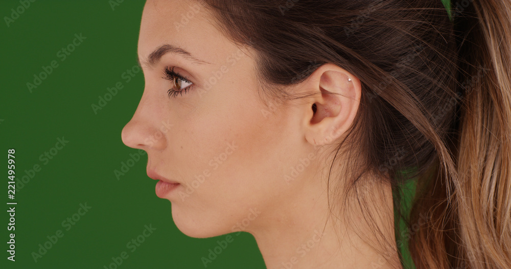 Close-up side profile of beautiful female model posing on green screen ...