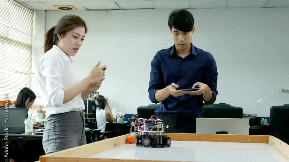 Teenager engineer using smartphone to control robot at laboratory ...