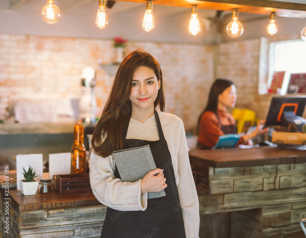 Portrait of Asian girl waitress holding menu wearing apron and standing ...