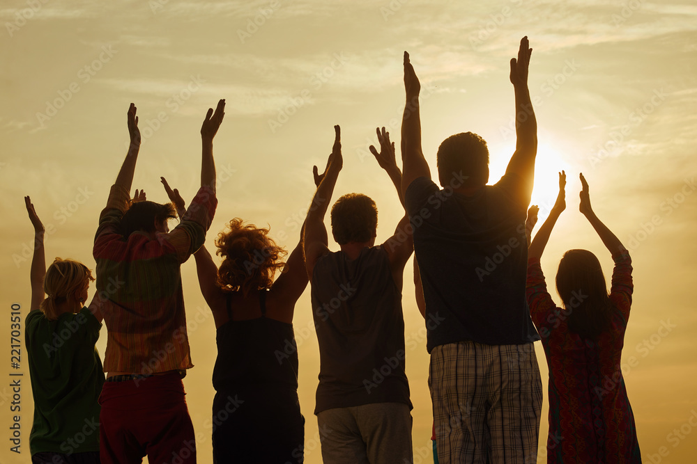 People raising hands up at the sky. Silhouette of family standing with ...