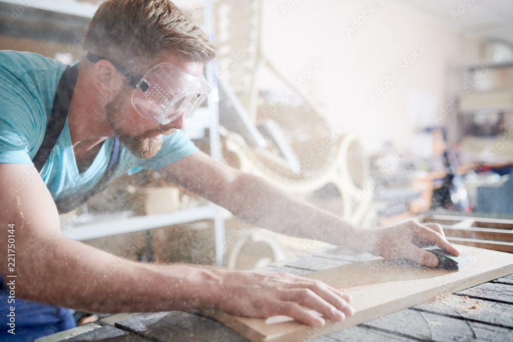 Craftsman in glasses busy with his work, he is using sandpaper in his ...